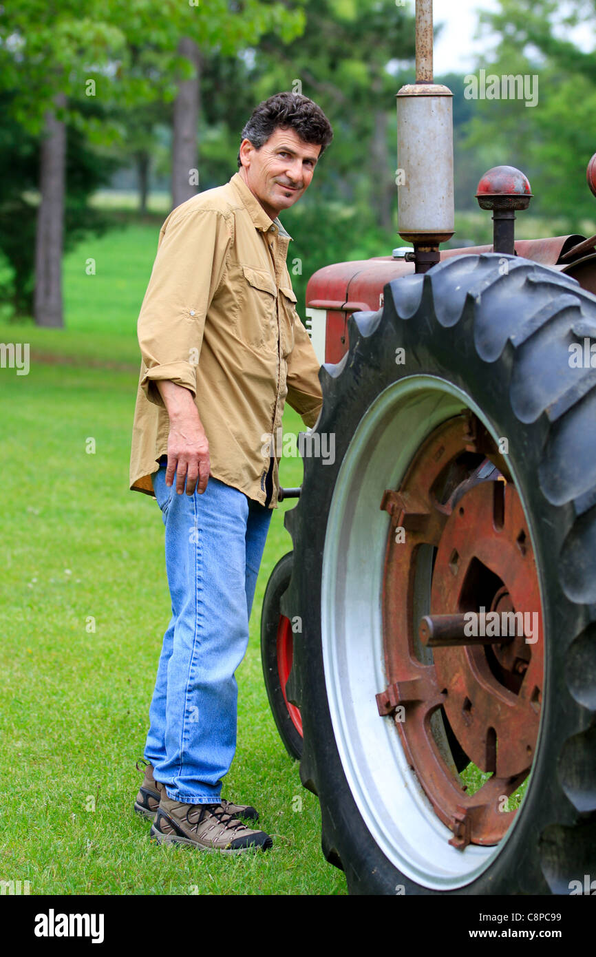 Hübscher 50 Jahre alter Mann neben einem Oldtimer-Traktor ...