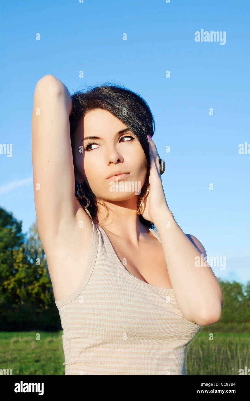 eine hübsche Frau posiert auf der Himmelshintergrund Stockfotografie ...