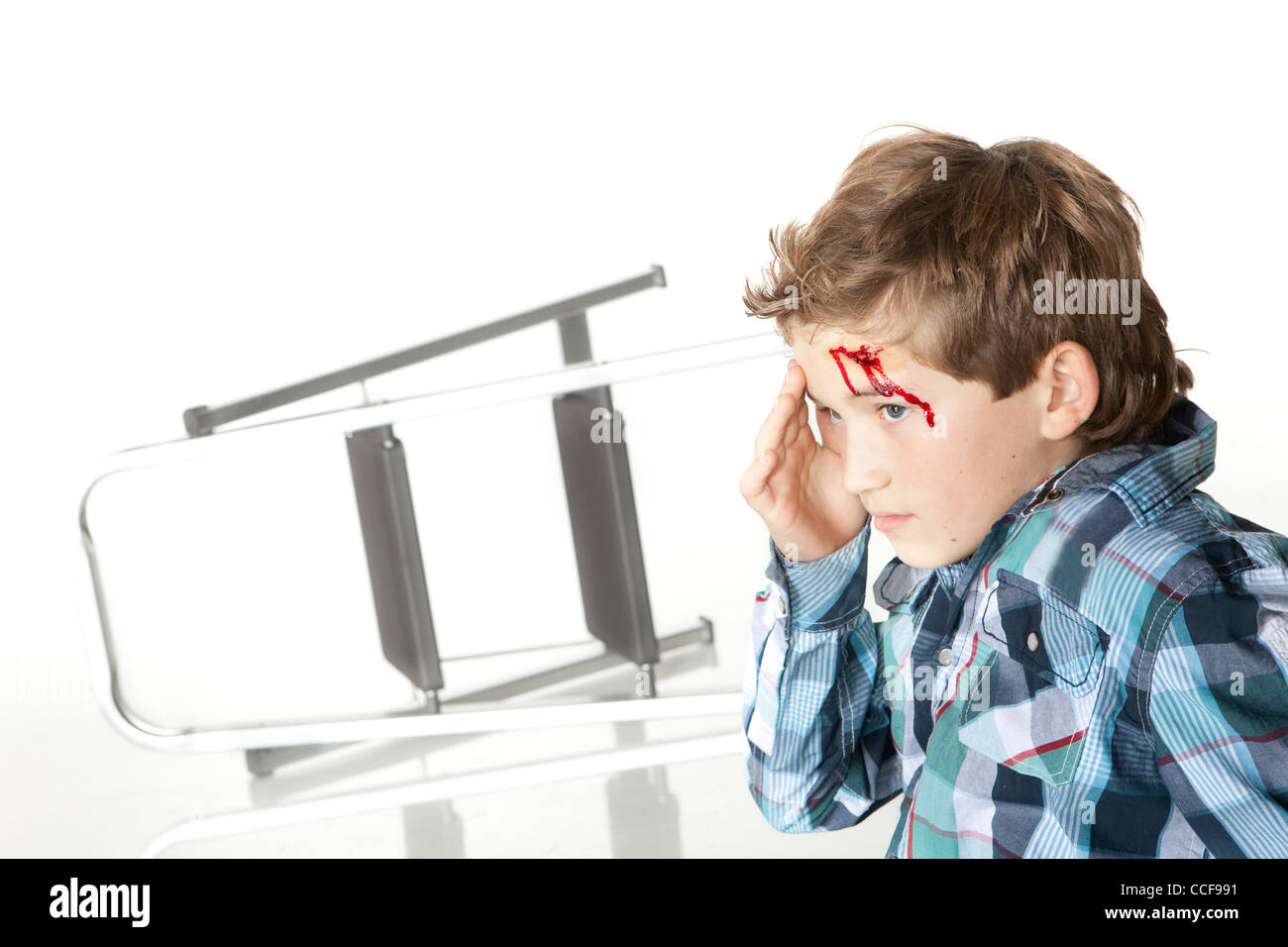 Kleiner Junge mit blutende Stirn sitzen mit Leiter im Hintergrund ...