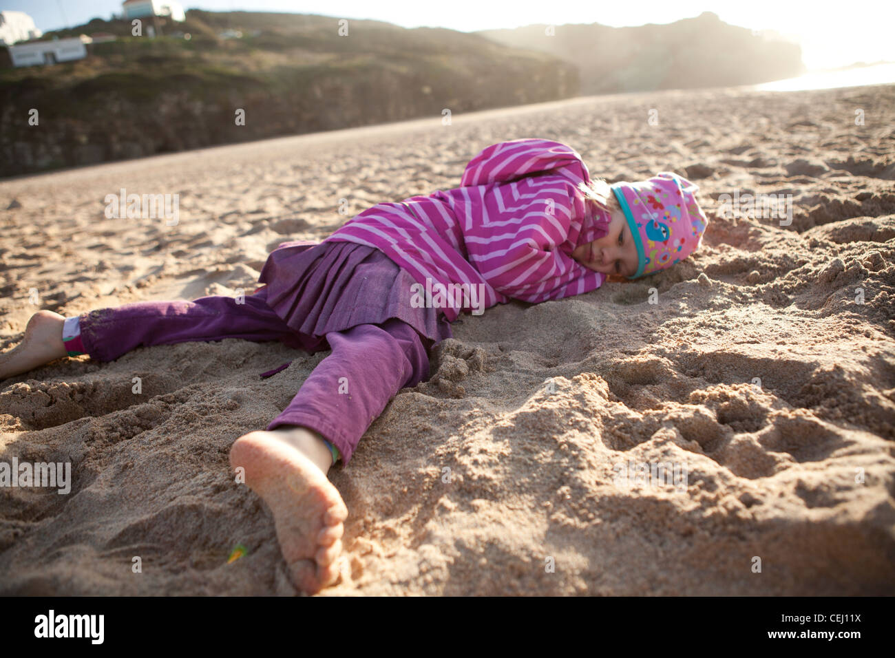 Niedliche kleine Mädchen im Sand am Strand liegen Stockfotografie - Alamy