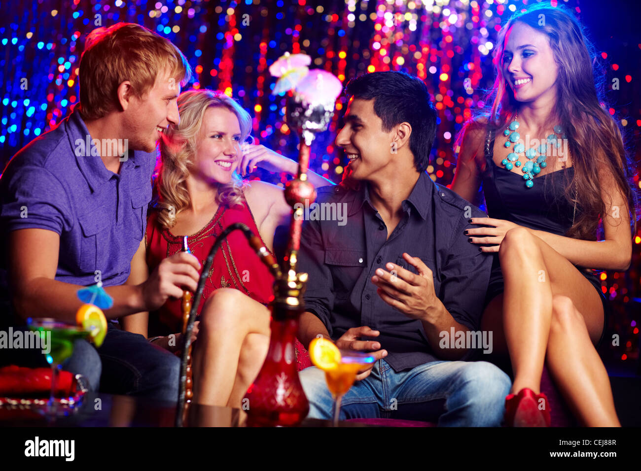 Glückliche Freunde trinken Cocktails und Rauchen Kalian im Nachtclub Stockfotografie - Alamy