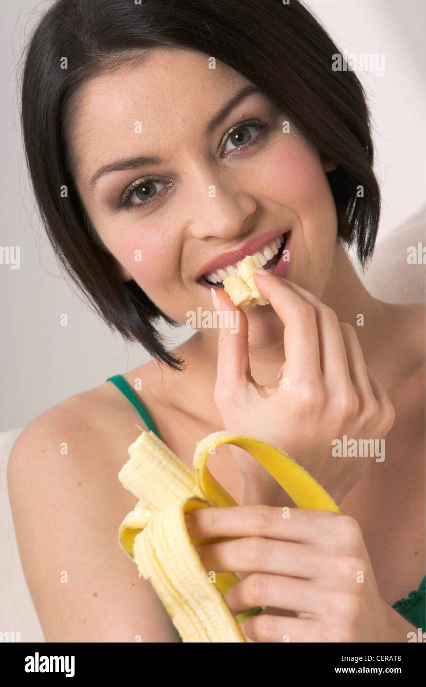 Weibchen mit Kinn Länge gerade brünette Haare Essen eine Banane auf ...