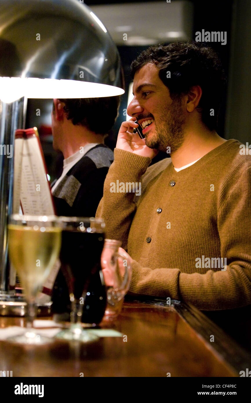 Ein junger Mann in der Kneipe spricht auf seinem Handy Stockfotografie ...
