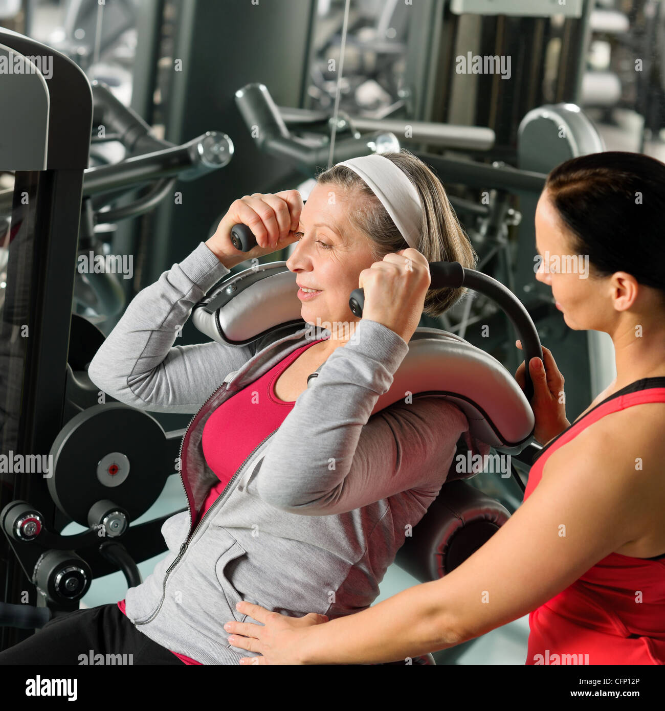 Ältere Frau im Fitnessstudio trainieren mit personal Trainer auf ...