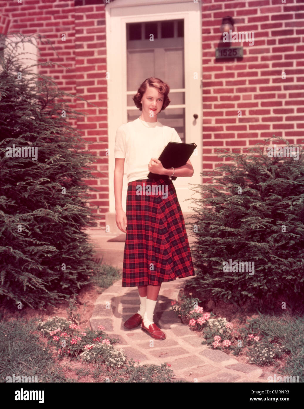 1950 1950S TEEN TEENAGER GIRL HOLDING SCHULBÜCHER HINUNTER BÜRGERSTEIG ...