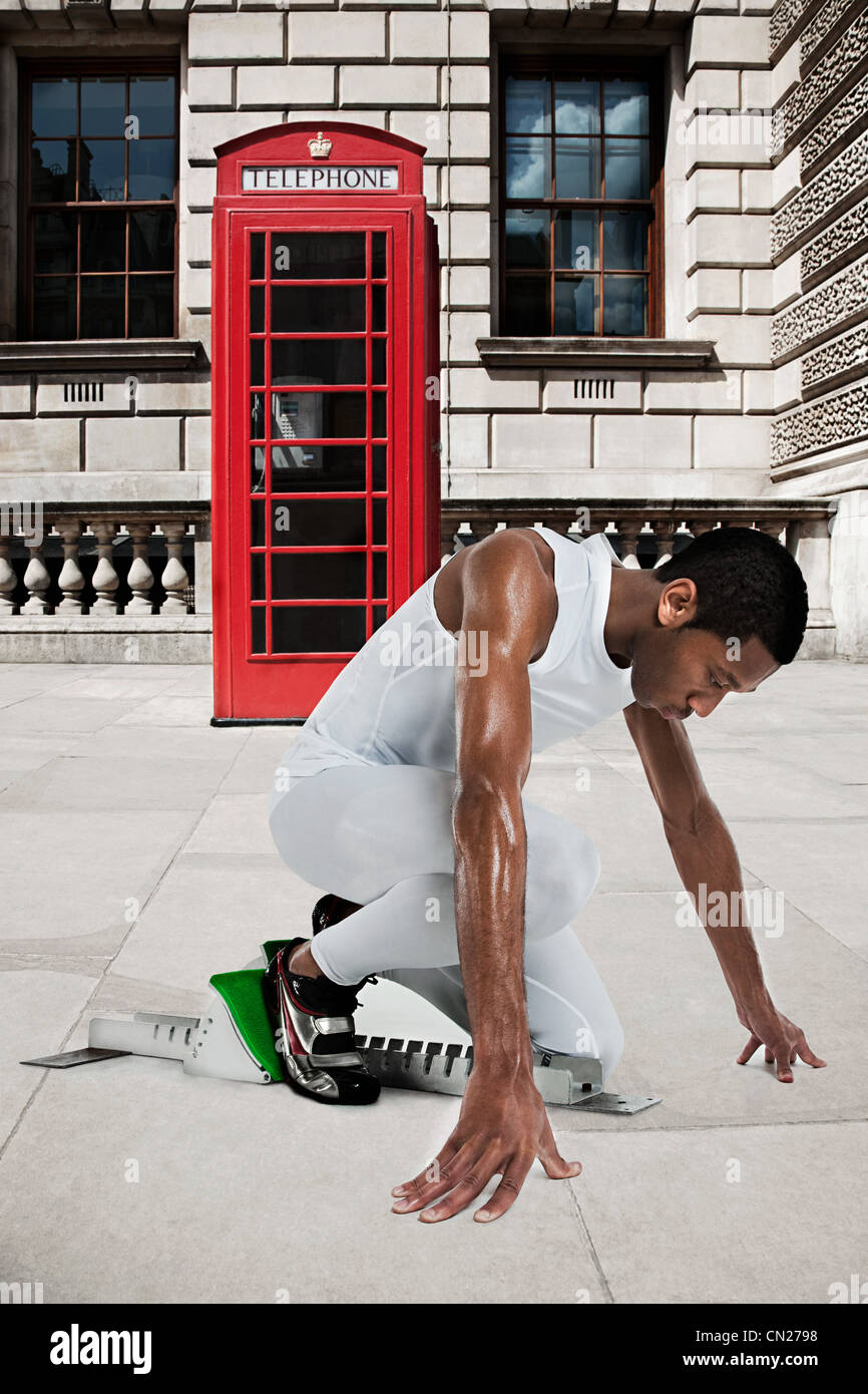 Olympia-Sprinter mit roten Telefon an Start-box im Hintergrund ...