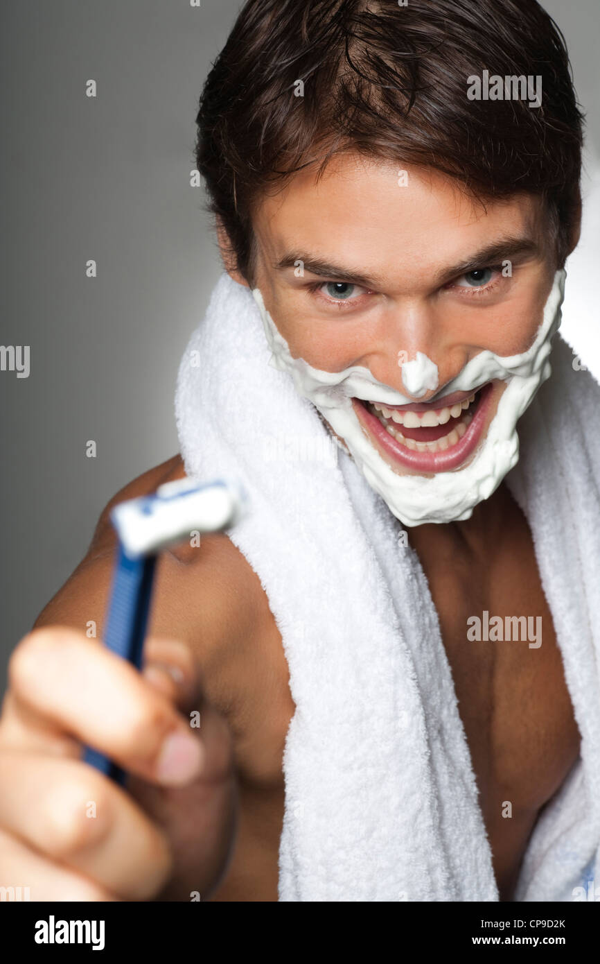 Porträt von gesund aussehender junger kaukasischen Mann lachend mit Rasierschaum auf Gesicht ...