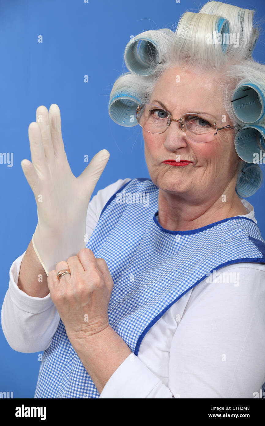Oma mit ihrem Haar in Rollen setzen auf einen Latex-Handschuh ...