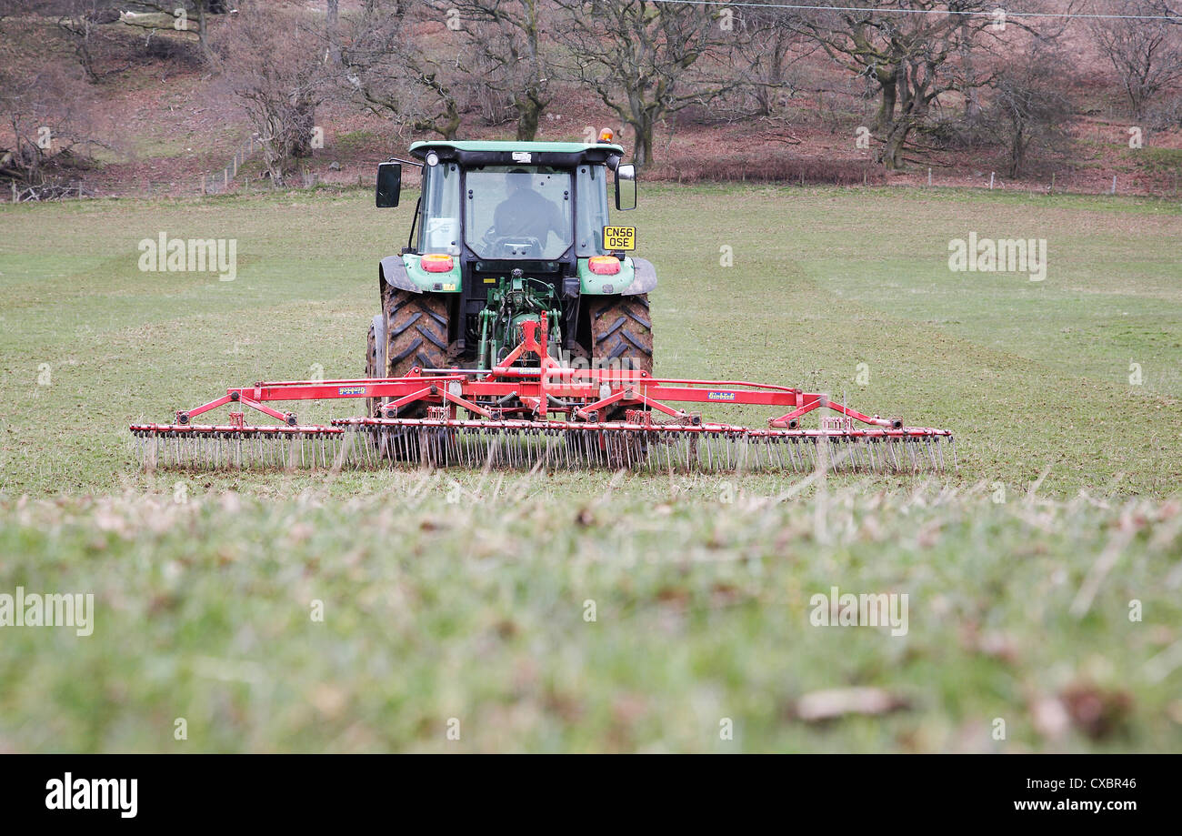 Landwirt in Traktor, ein Feld mit Rasen Vertikutieren Eggen Anlage auf ...