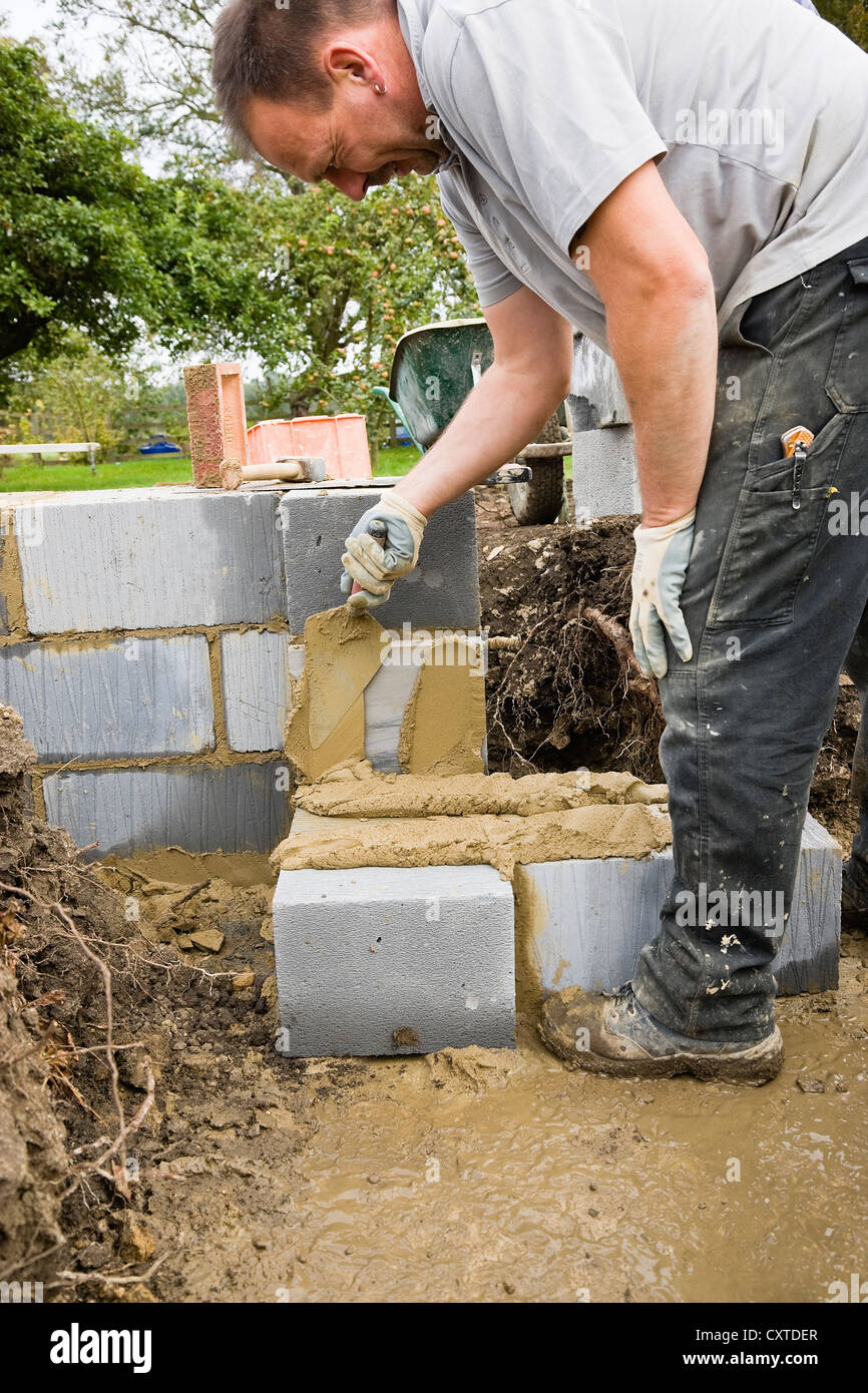 Maurer Betonblock mit einer Kelle auf eine englische Baustelle Mörtel ...
