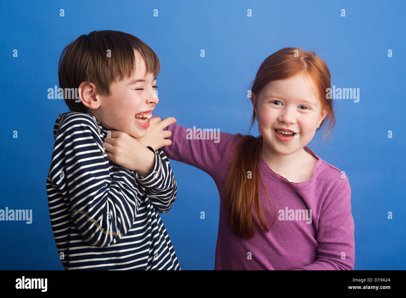 Mädchen 6 kitzelt junge 8 Hals auf einen blauen Hintergrund. Junge ...