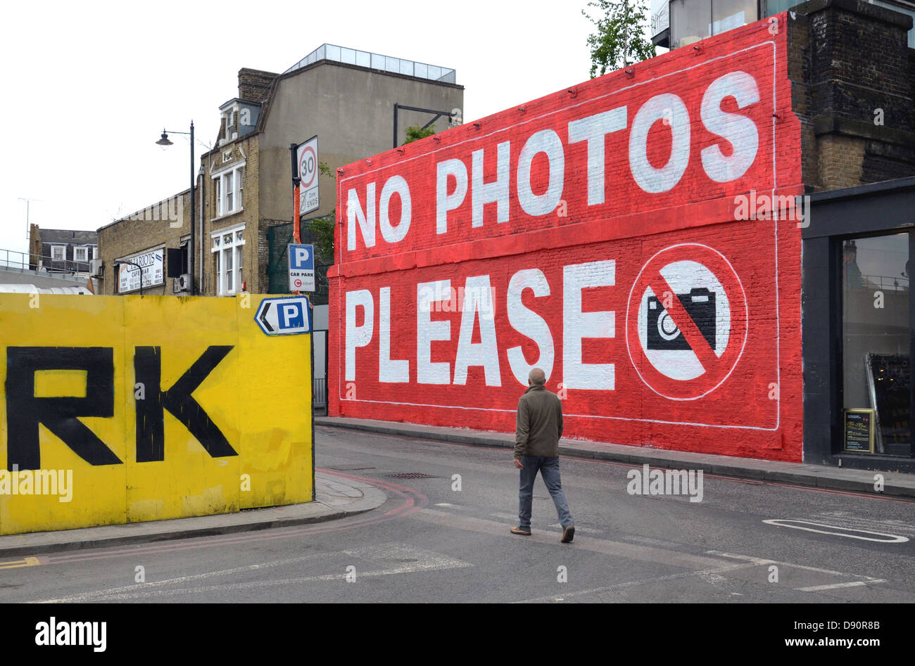 Ein Mann geht durch eine große Sign. "No Fotos bitte" an der Wand des ...