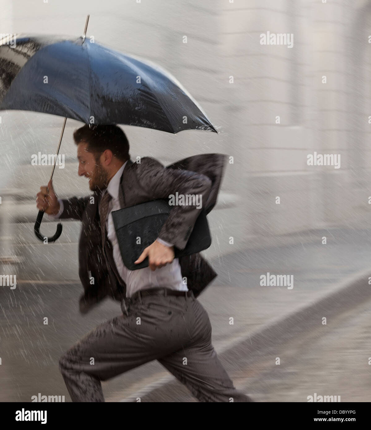 Geschäftsmann mit Schirm im Regen laufen Stockfotografie - Alamy