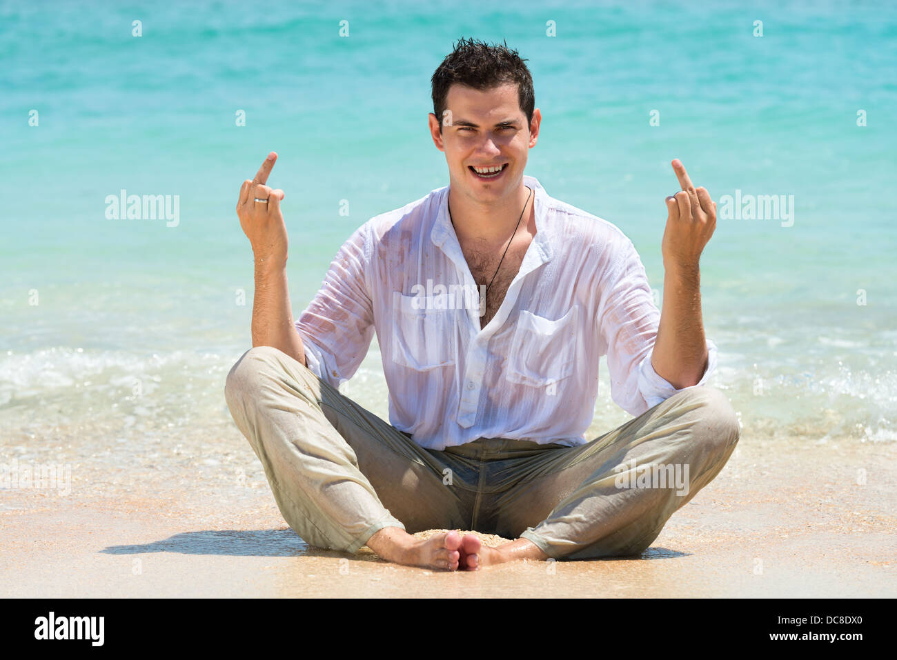 Glücklicher Mann zeigt Mittelfinger und genießen am Strand mit Meer im ...