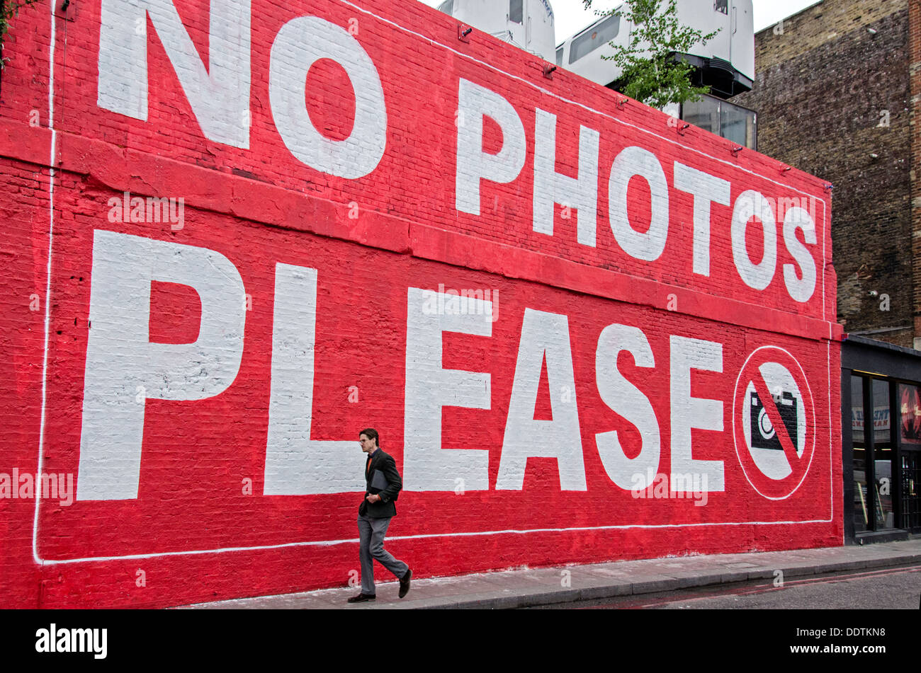 Ein Mann geht durch eine große Sign. "No Fotos bitte" an der Wand des ...