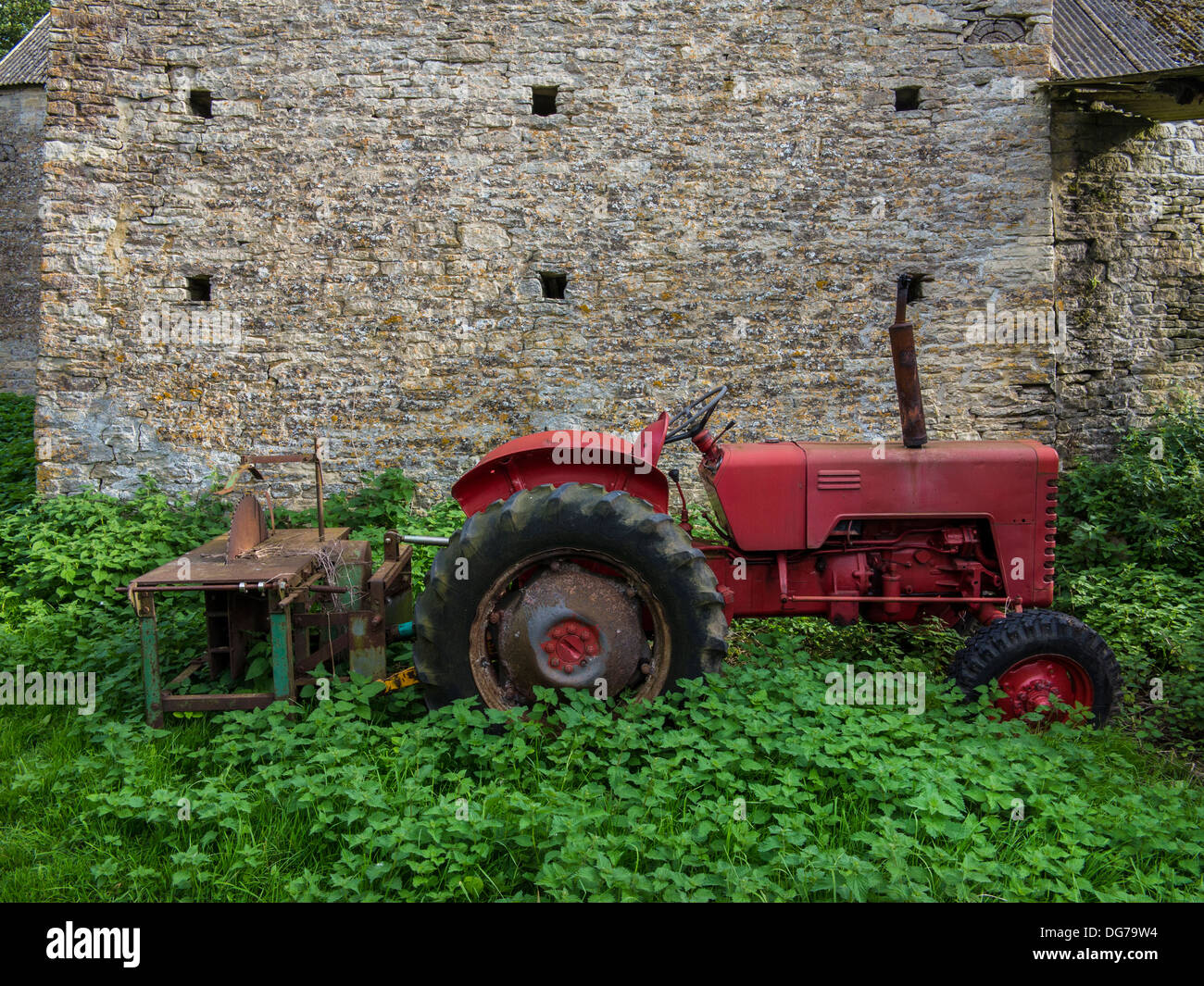 Eine alte rote Traktor geparkt in einem Feld von Unkraut vor einer ...