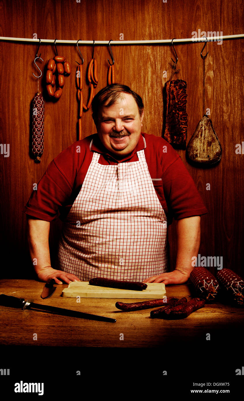 Fett Metzger lächelnd mit seinen Händen aufgestützt auf einer Bank in ...