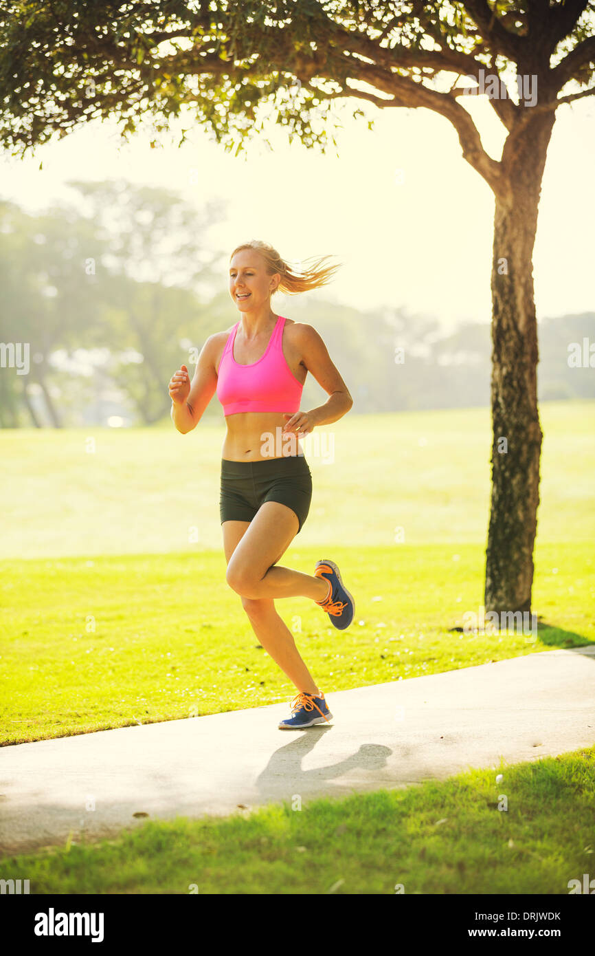 Athletic fit junge Frau läuft im freien früh am Morgen im Park Joggen ...