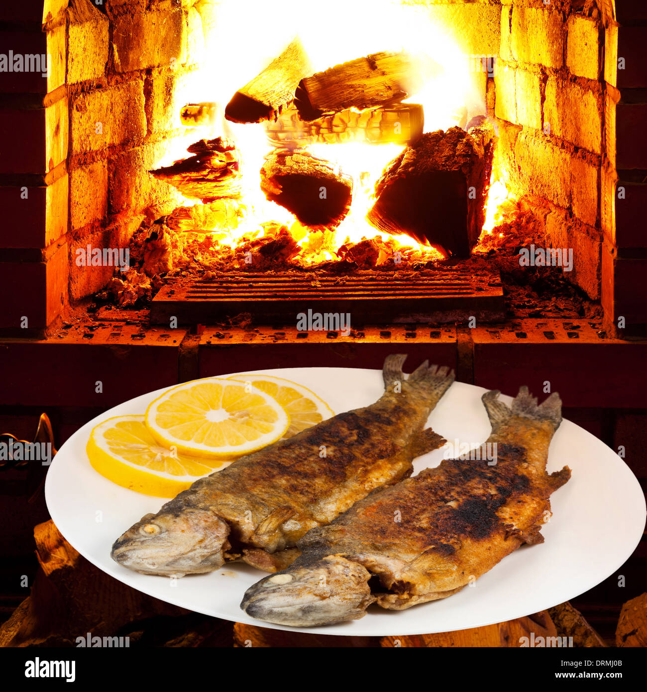Gebratene Fluss Forelle Fisch auf Teller und offenem Feuer im Holzofen ...