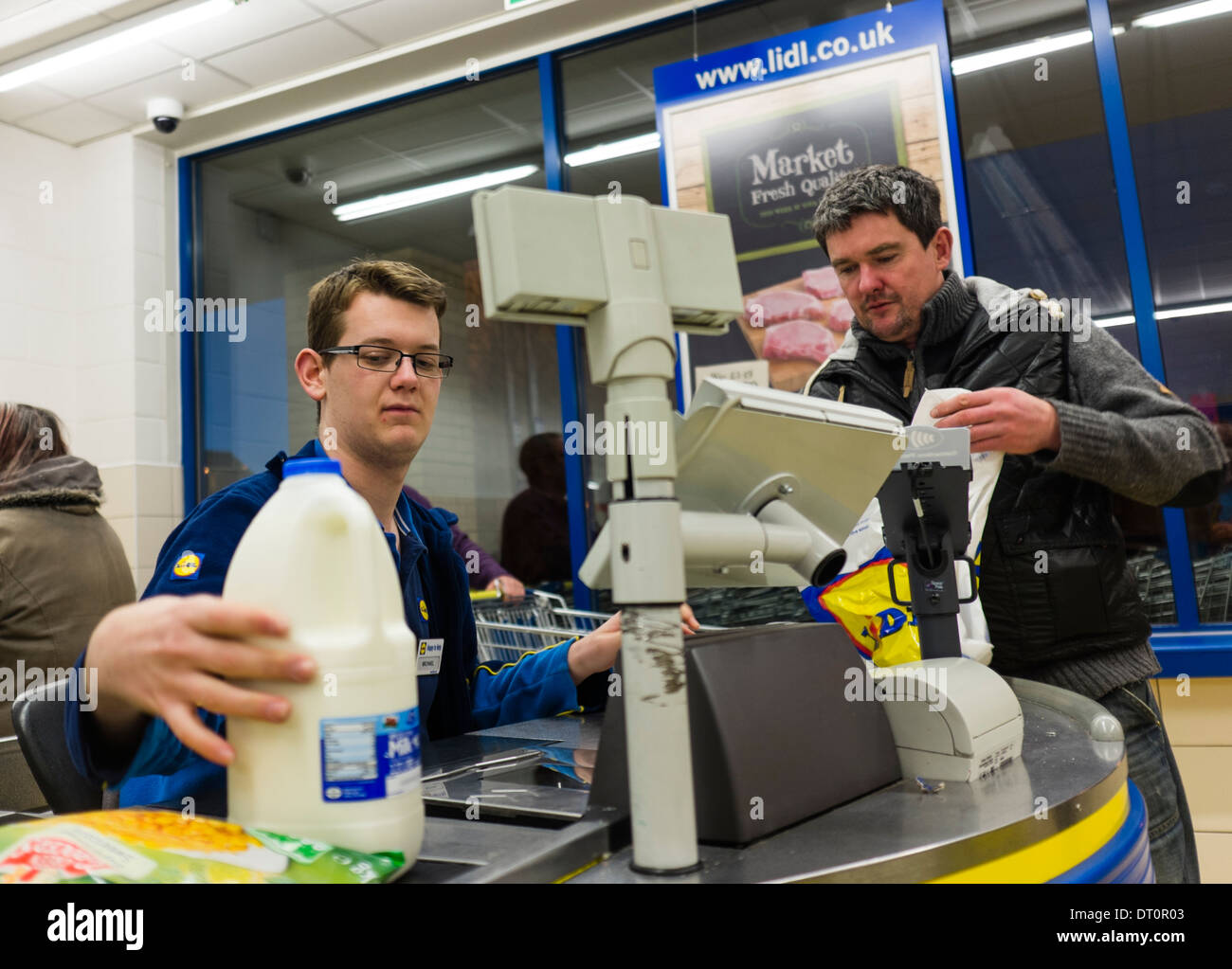 Eine männliche Kasse Bedieners an einem Seitenarm des Lidl-Supermarkt ...