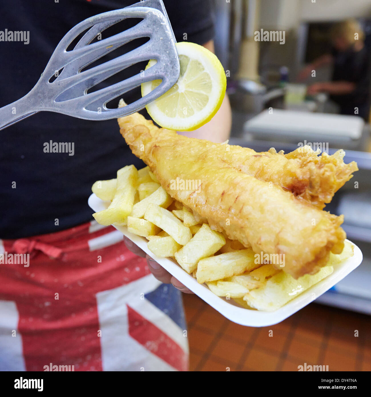 Mitarbeiter mit einer Zitronenscheibe und Portion Fish & Chips im Happy ...