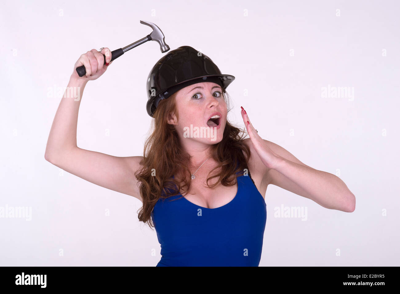 Junge Frau hält einen Hammer und einen Schutzhelm tragen ...