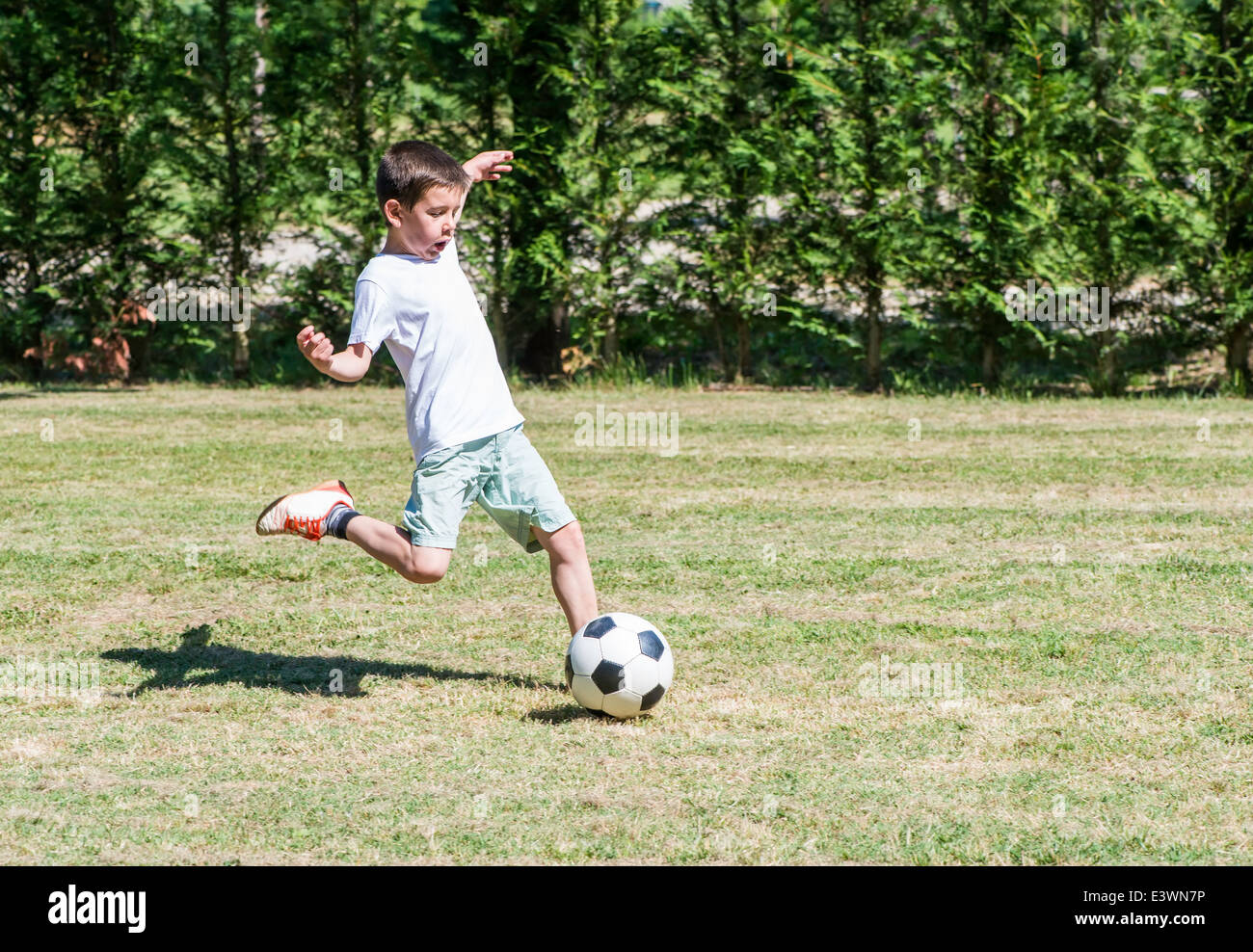 Kinder spielen Fußball in einem Stadion. Bäume auf dem Grund ...