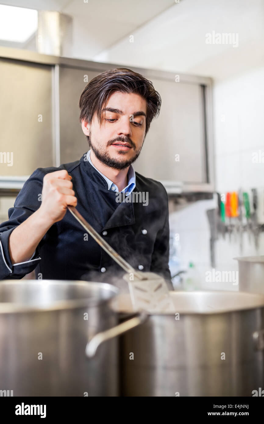 Profi-Koch in einer Großküche ein Gemüse unter Rühren braten über einem ...