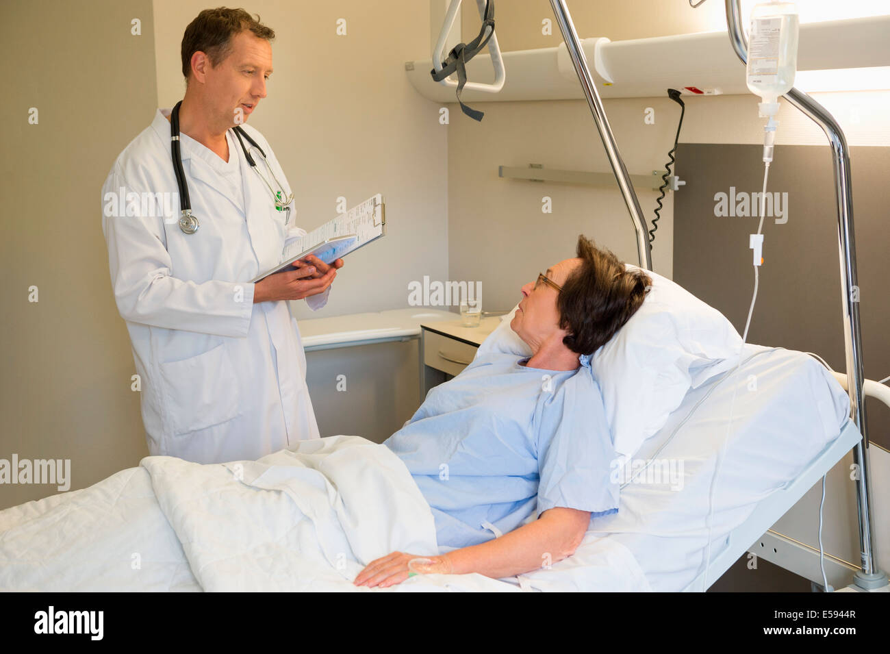 Männlichen Arzt im Gespräch mit Patienten am Krankenbett ...