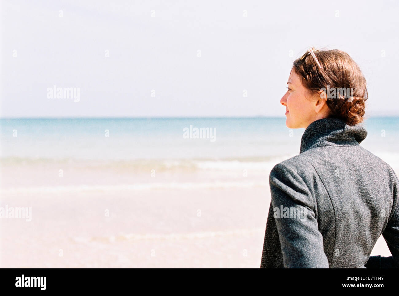 Eine Frau in eine graue Jacke, Blick auf den Strand und das Meer ...