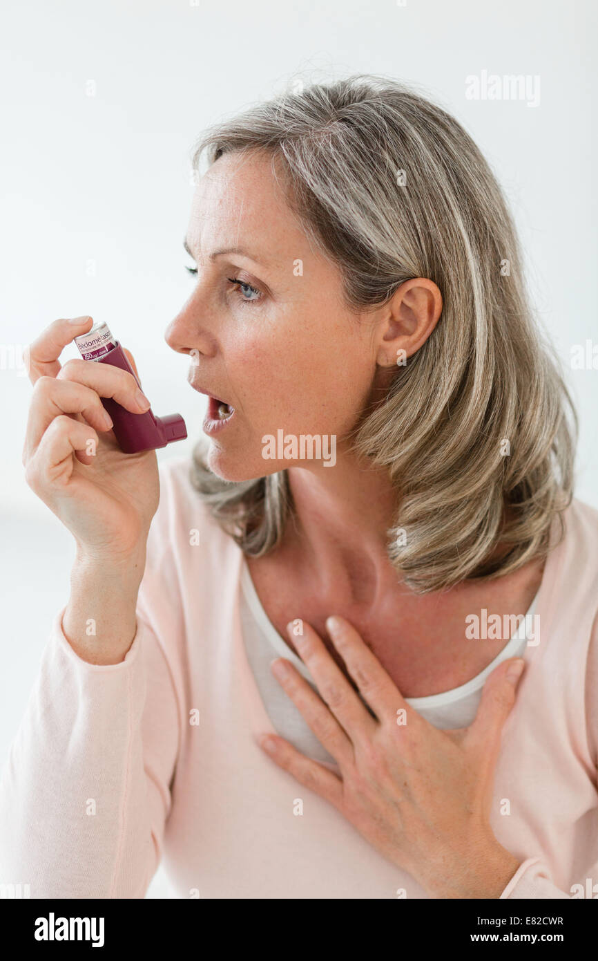 Frau mit einem Aerosol-Inhalator, der Bronchodilatator zur Behandlung ...