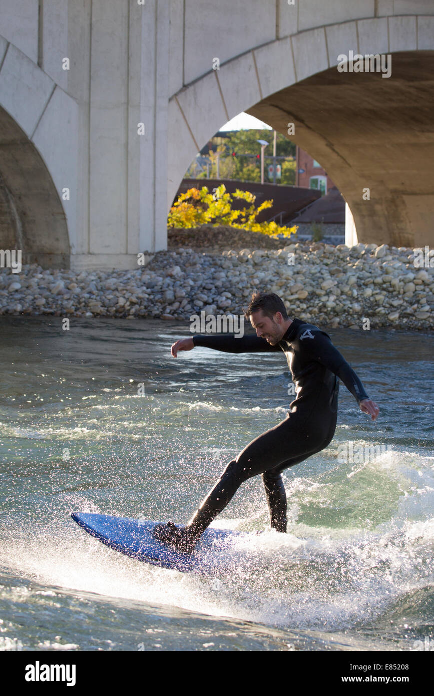 Mann surft auf dem Bow River neben der Louise Bridge im Stadtzentrum ...