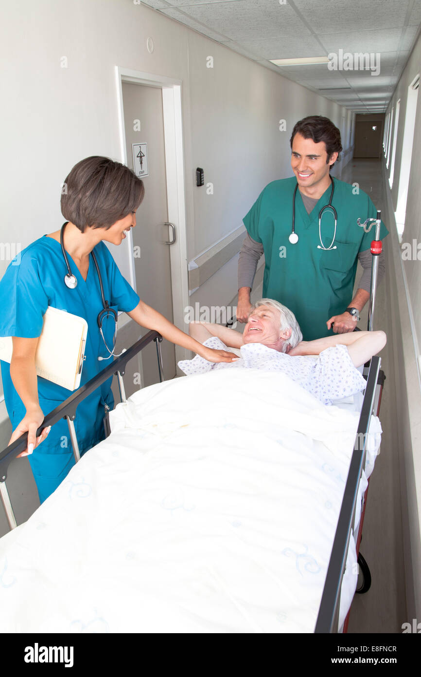 Zwei Ärzte, die Patienten am Bett entlang Krankenhausflur verschieben ...