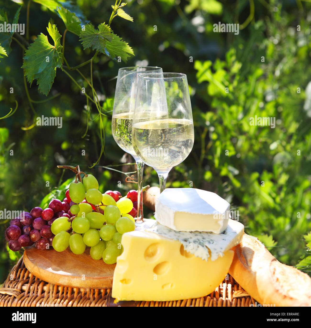 Verschiedene Arten von Käse, Brot, Trauben und zwei Gläser Weißwein ...