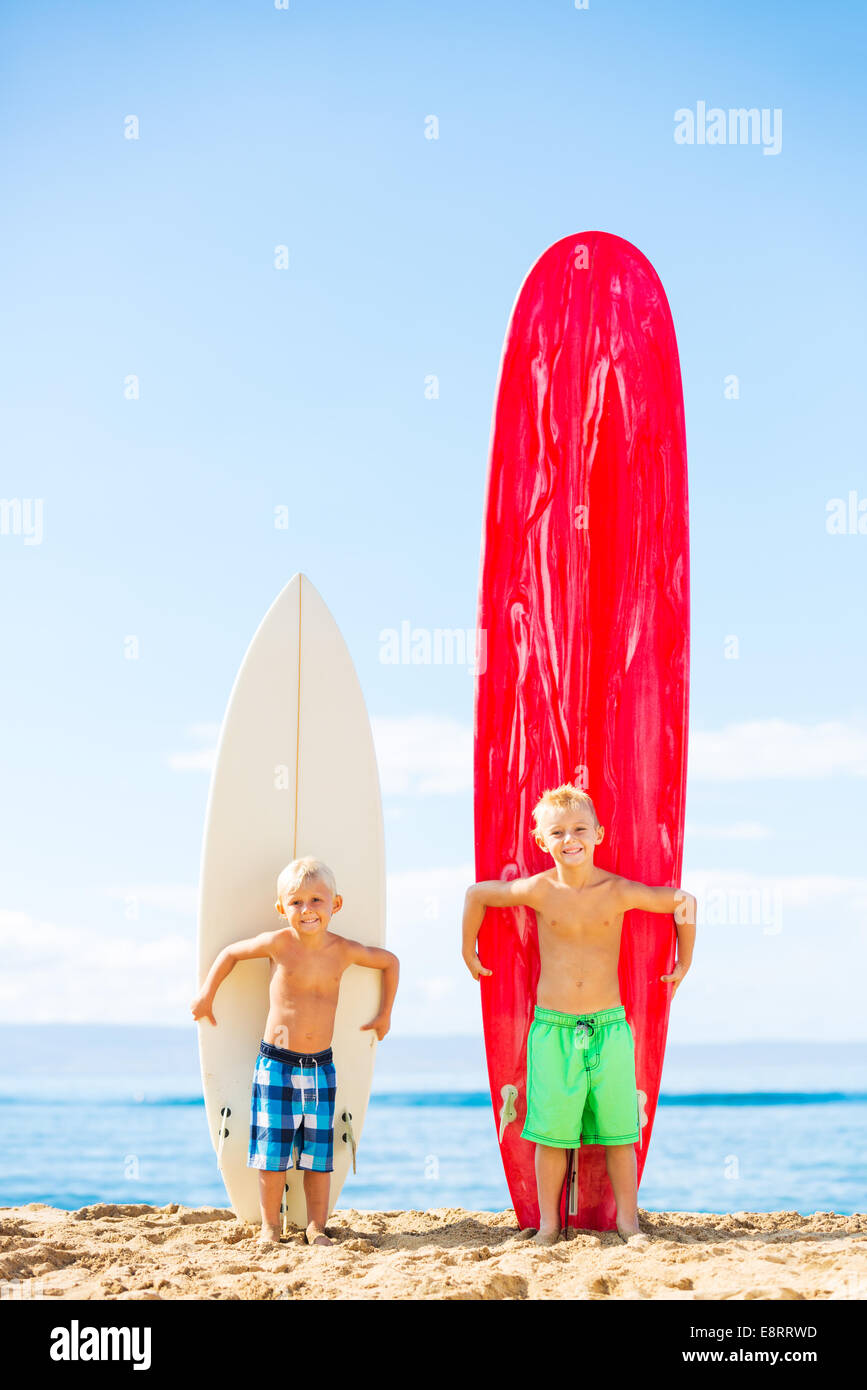 Süße junge Jungs mit Surfbrettern am Strand von Hawaii. Gehen surfen ... Süße junge Jungs mit Surfbrettern am Strand von Hawaii. Gehen surfen ...