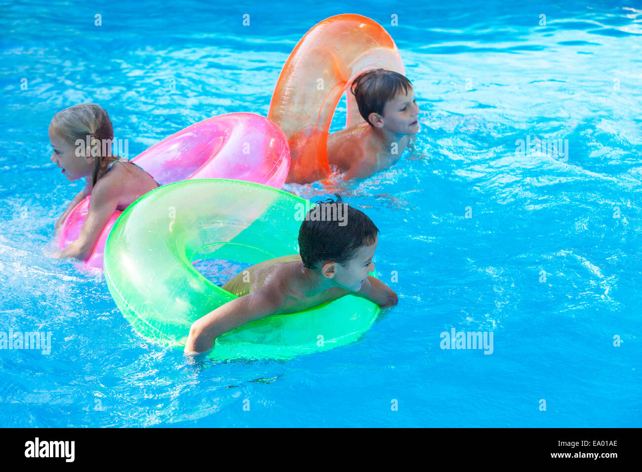 Drei Kinder spielen im Garten Pool mit aufblasbaren Ringen ...