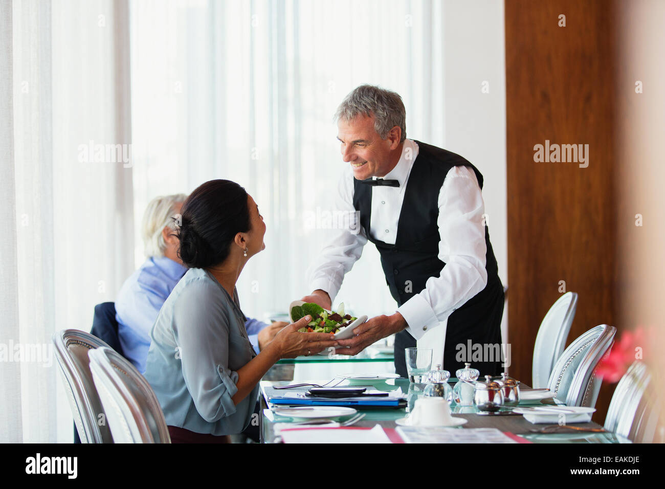 Lächelnden Kellner servieren Salat, Frau sitzt am Tisch im restaurant ...