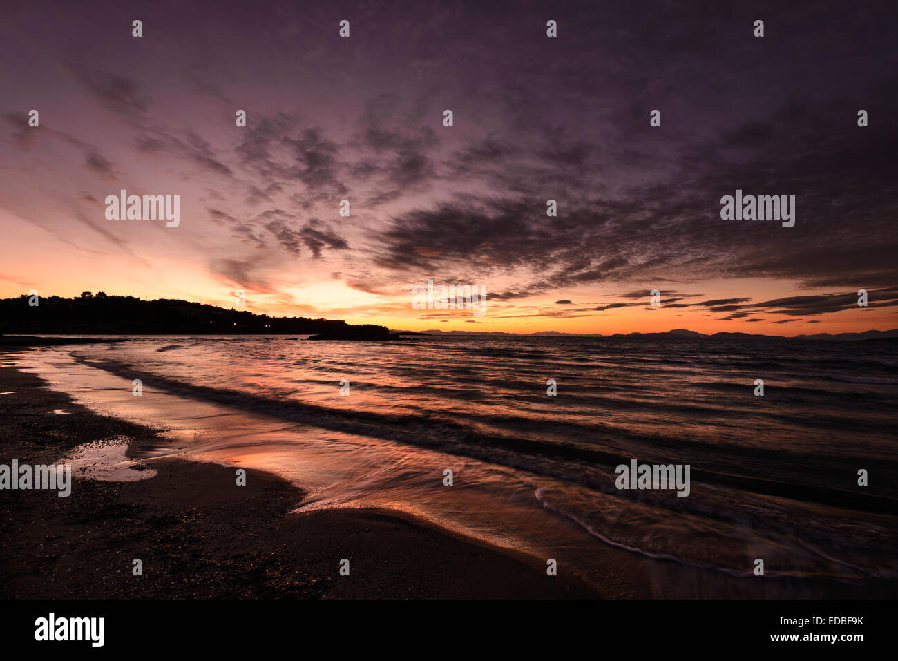 Wellen des Meeres bilden eine Herzform am Strand bei Sonnenuntergang ...