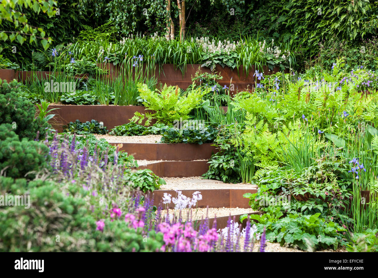 Kies mit Corten-Stahl durch abfallenden Garten mit Gräsern, kleine ...