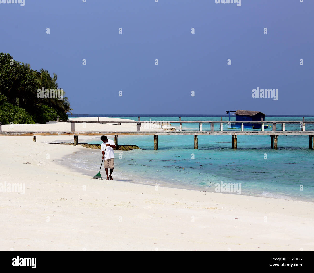 Ein Mitarbeiter Rechen, Algen und Schmutz von den weißen Sand des ...