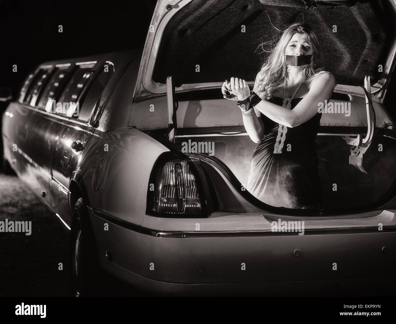 Attraktive Blondine im Kofferraum der Limousine, Hände gefesselt und ...