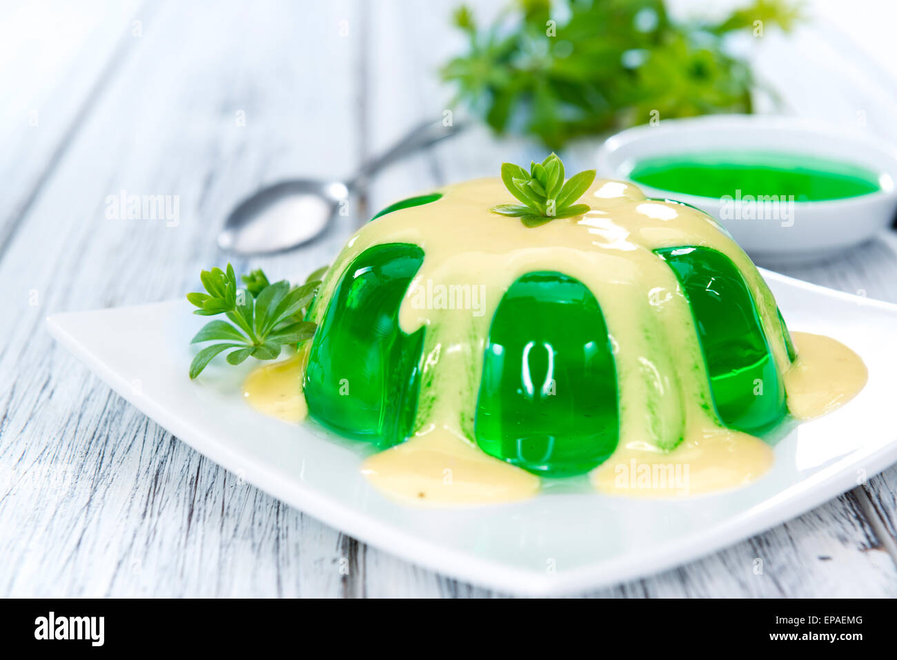 Waldmeister-Gelee mit Vanillesauce (auf hölzernen Hintergrund ...
