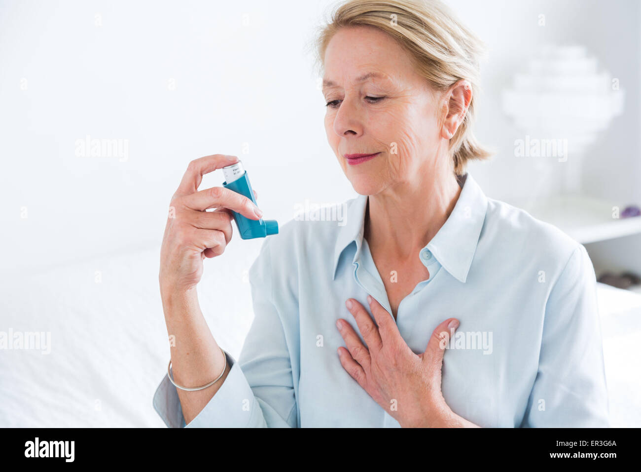 Frau mit einem Aerosol-Inhalator, der Bronchodilatator zur Behandlung ...