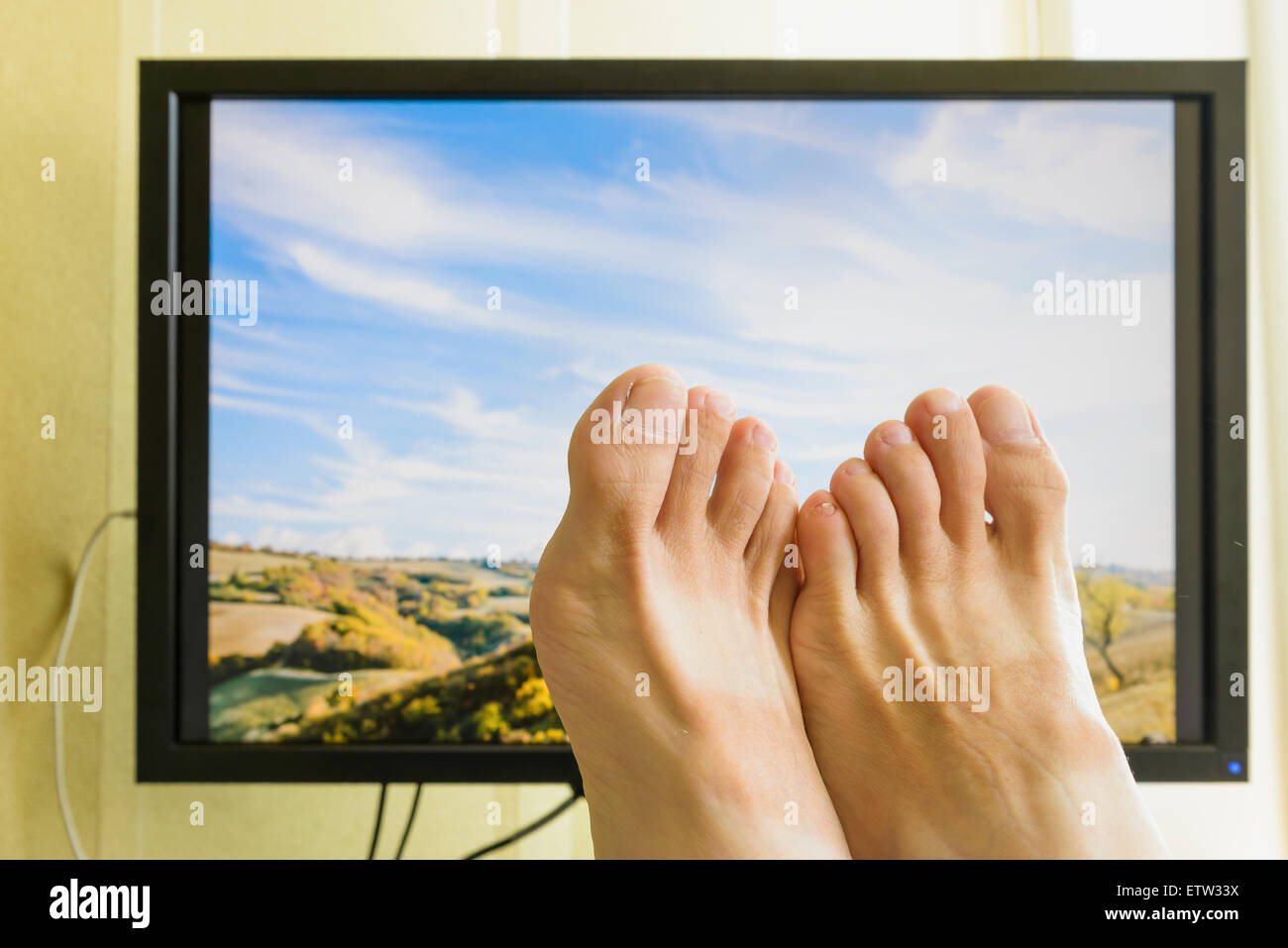 Mannes Füße vor einem Computer-Monitor mit einer schönen sonnigen ...