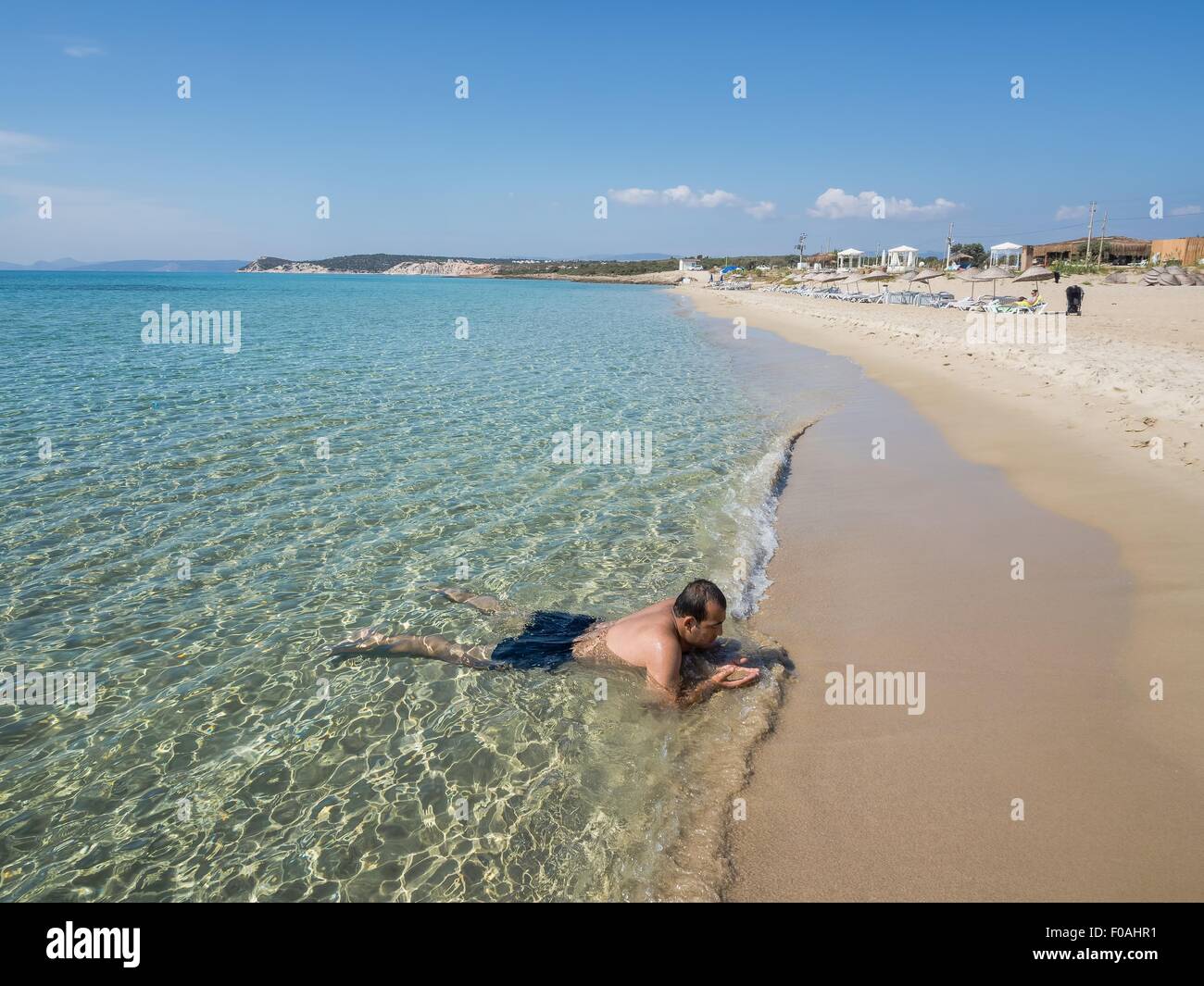 Mann liegt am Strand von Altinkum in Alacati, Cesme Halbinsel, Türkei ...