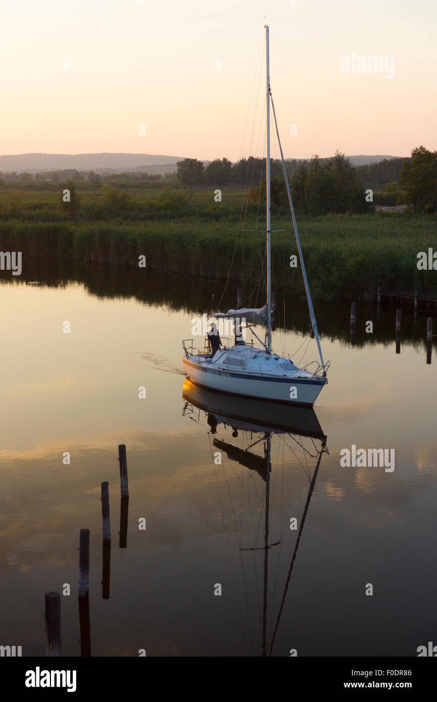 Ein Segelboot, das sich in stillem Wasser spiegelte, mit zwei Personen ...
