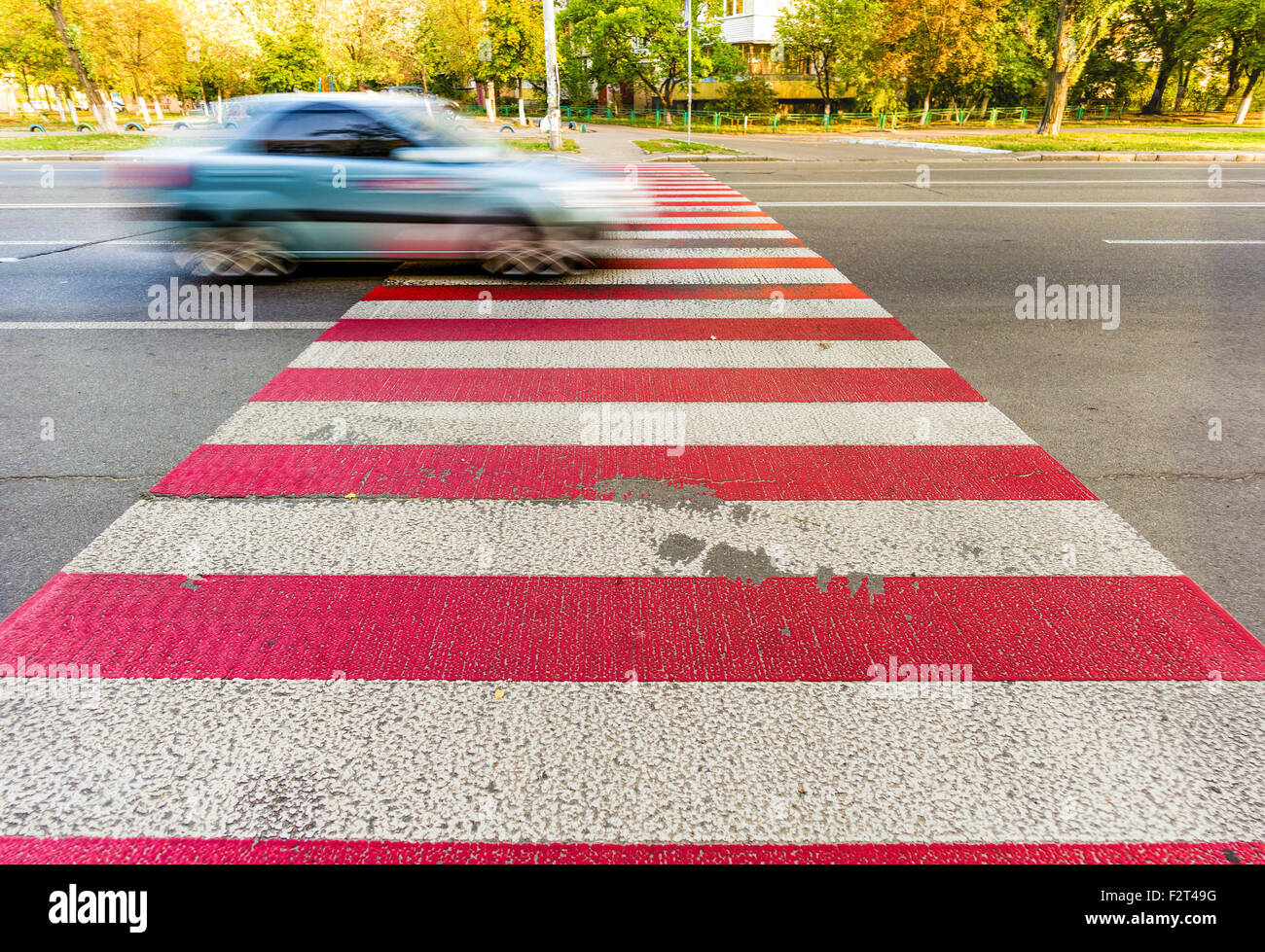 Graues Auto auf einem roten und weißen Fußgängerüberweg auf blau ...