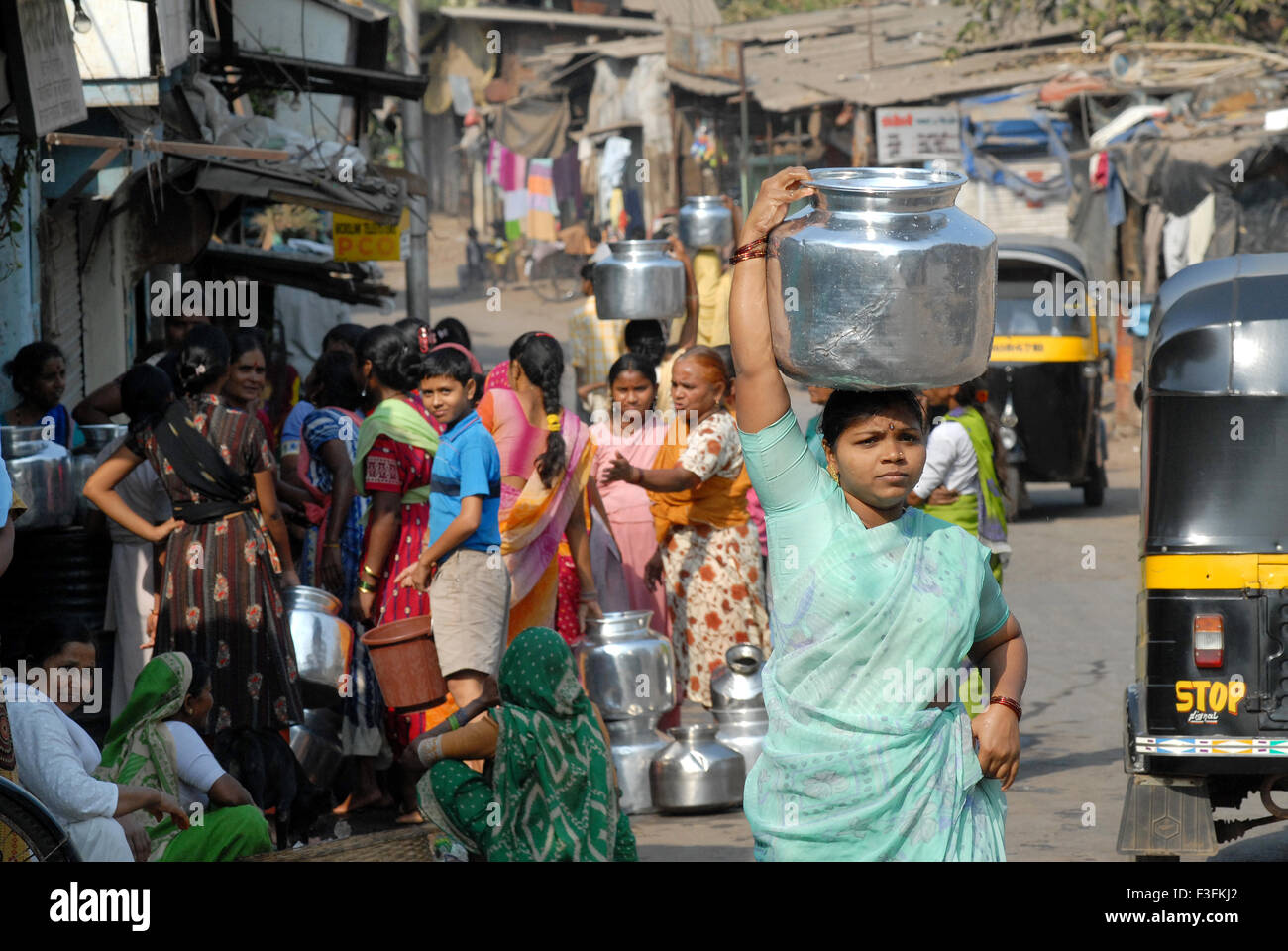 Frauen tragen auf dem Kopf in einem Slum in Chembur Trinkwasser in ...