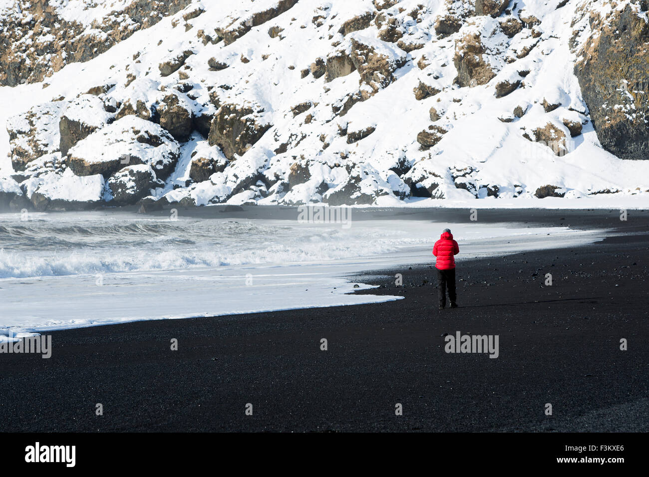 Frau Spaziergänge entlang der schwarzen Sandstrand in Vik, Island im ...