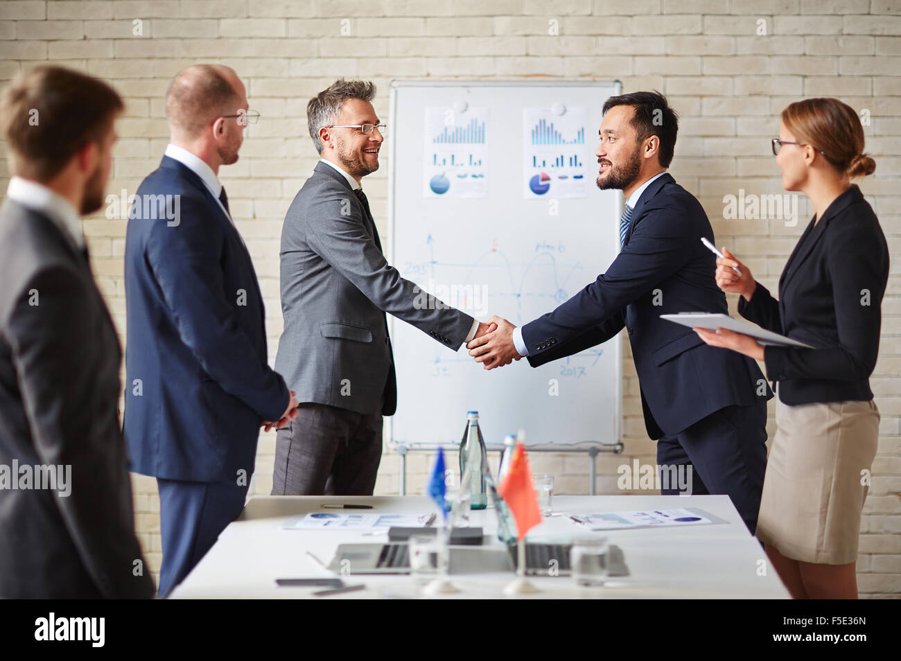 Ausländische Geschäftspartner begrüßen einander durch handshaking ...